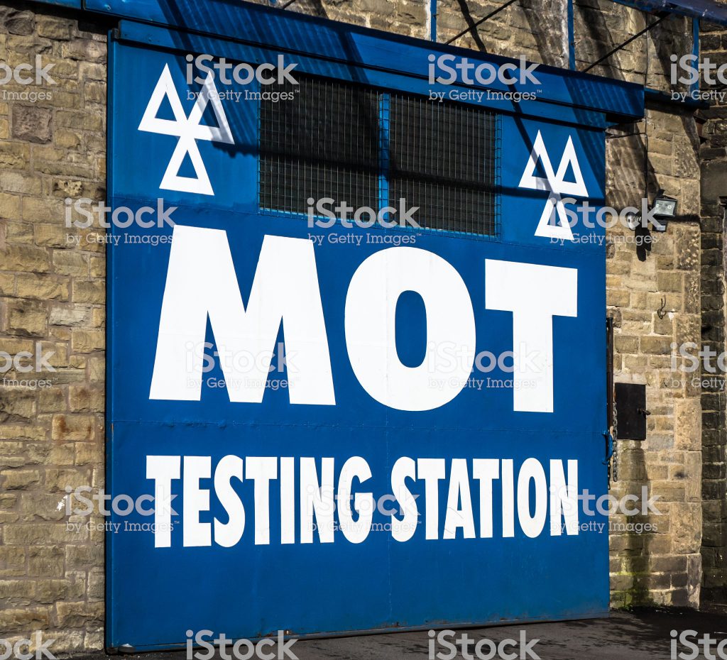 Large sign on the doorway of an MOT testing station in the UK. - Green Flag